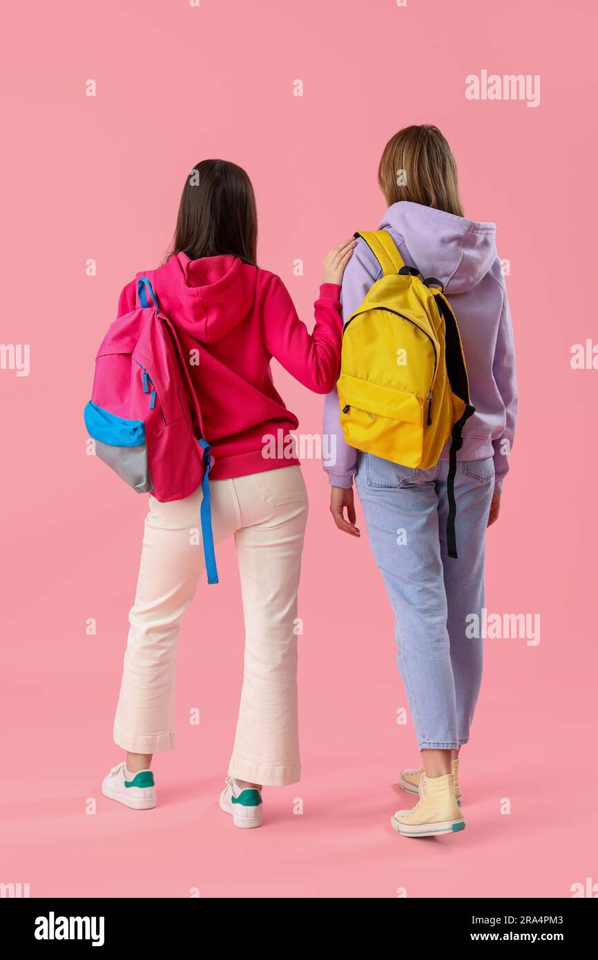 Female students with backpacks on pink background, back view Stock ...