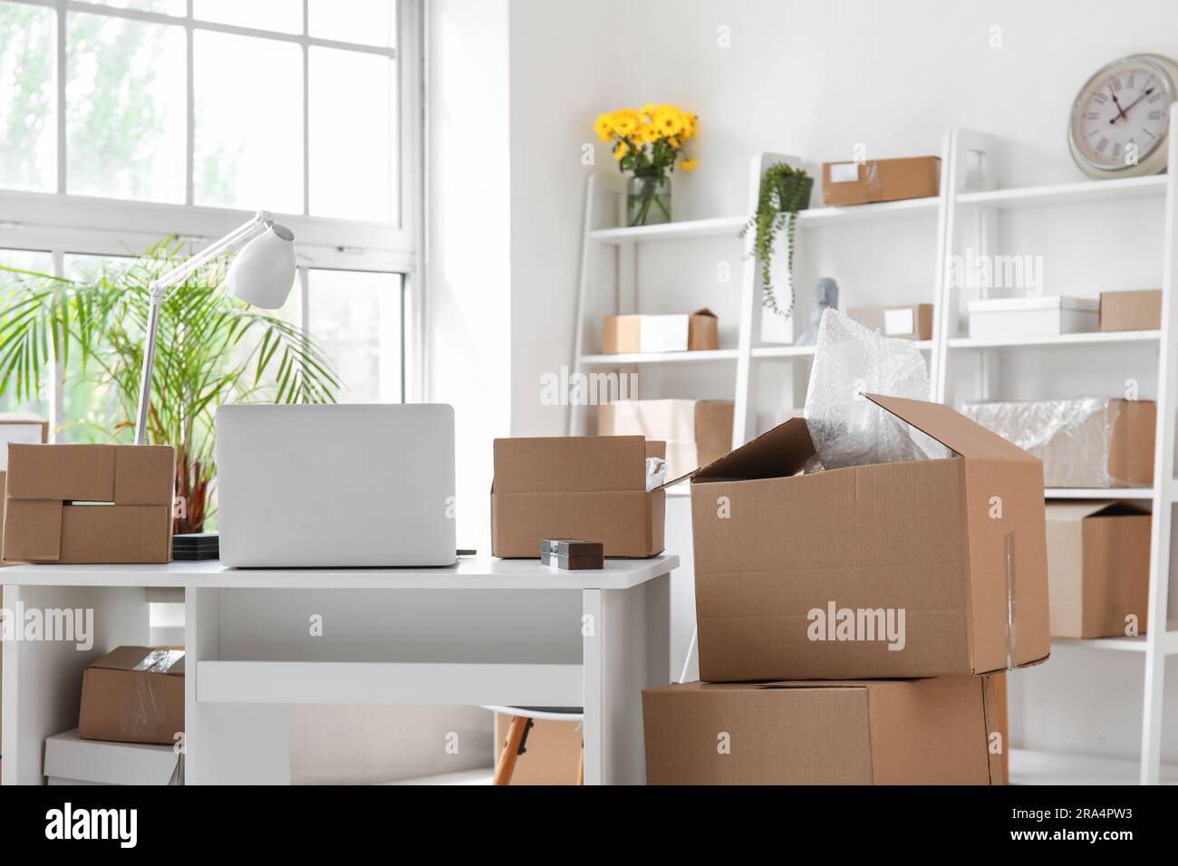 Workplace with laptop and parcels in office Stock Photo - Alamy