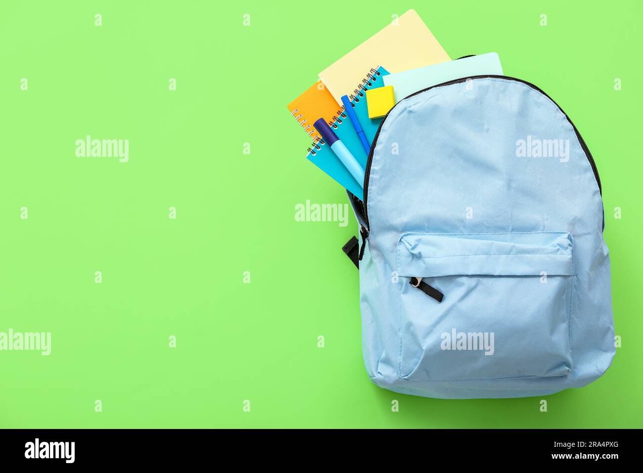 Blue school backpack with notebooks and markers on green background ...