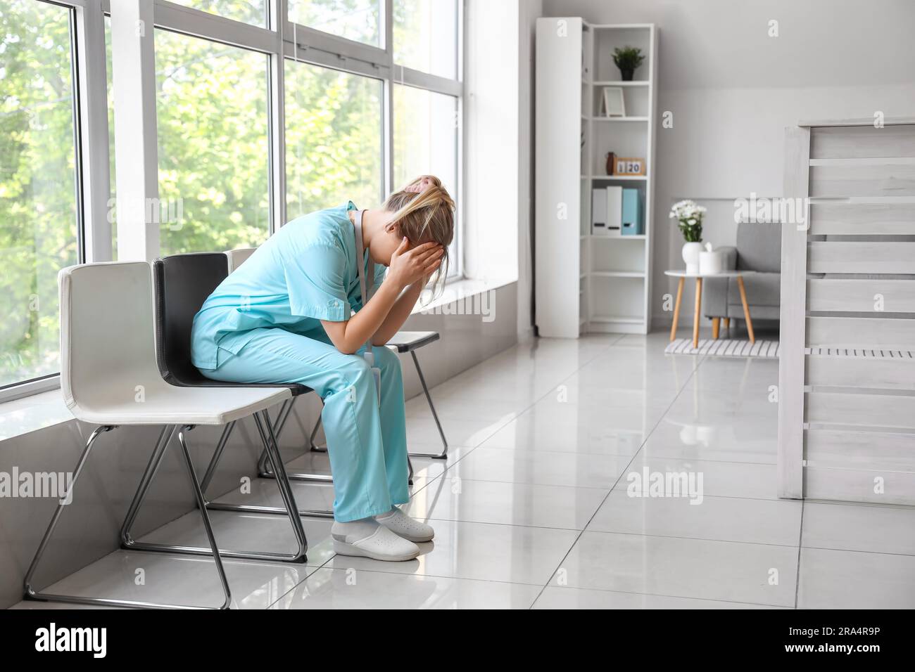 Sad female medical intern sitting in clinic Stock Photo - Alamy