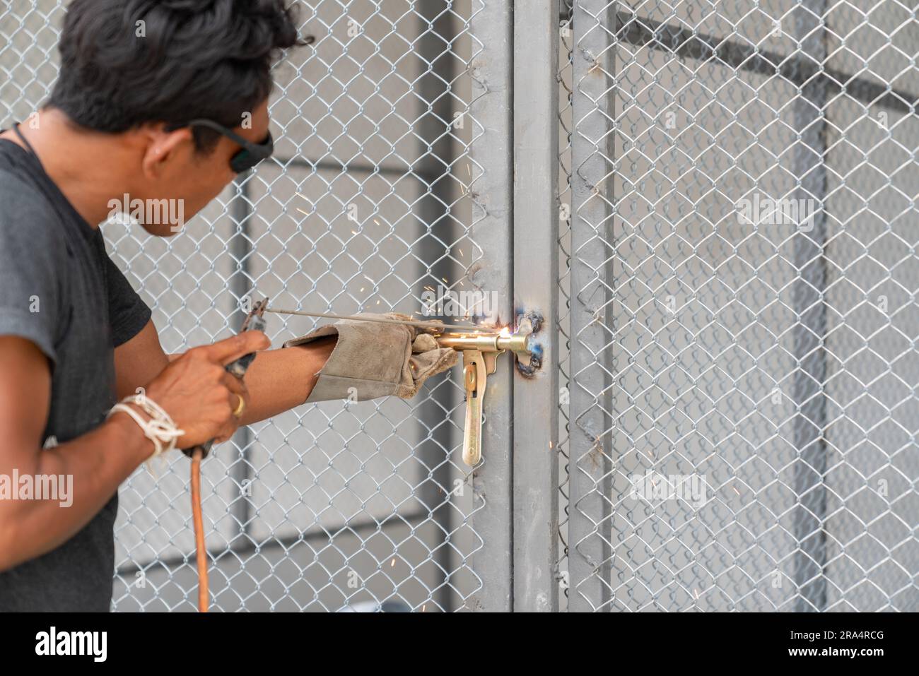 Welder welding a metal net door lock with gloves in construction site ...
