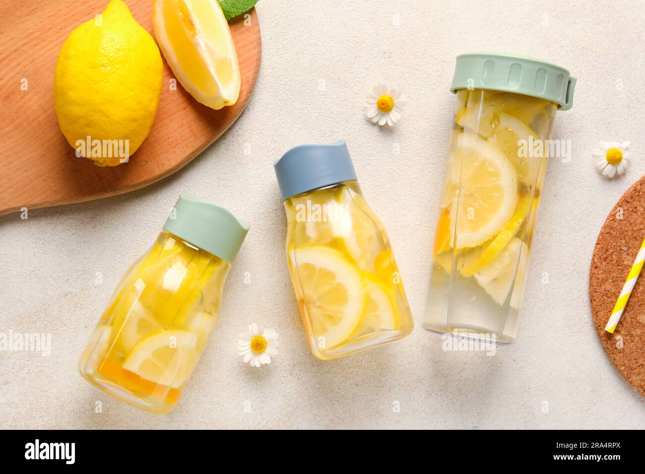 Bottles of infused water with lemon on light background Stock Photo - Alamy