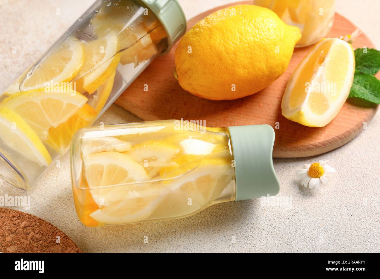 Bottles of infused water with lemon on light background Stock Photo - Alamy
