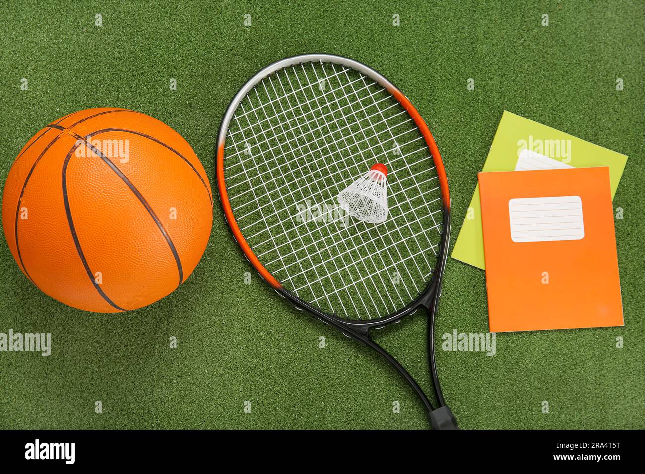 Badminton shuttlecock with racket, ball and notebooks on color ...