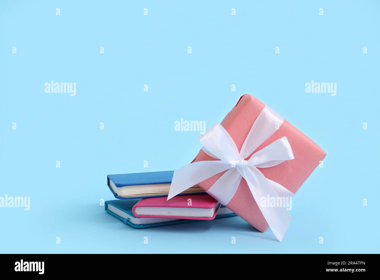 Gift box with notebooks on blue background Stock Photo - Alamy