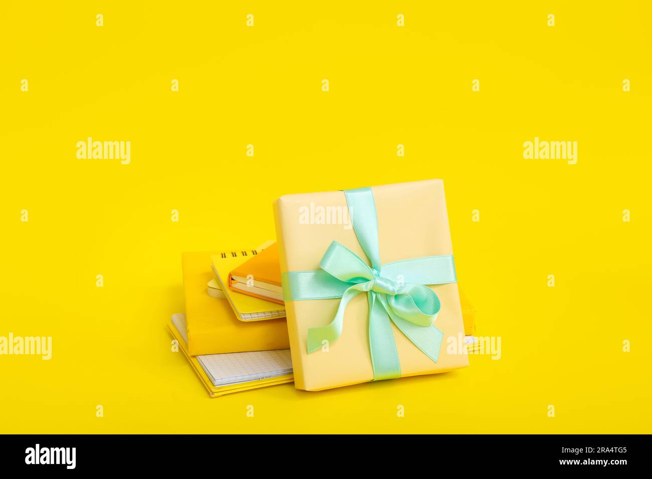 Gift box with different notebooks on yellow background Stock Photo - Alamy