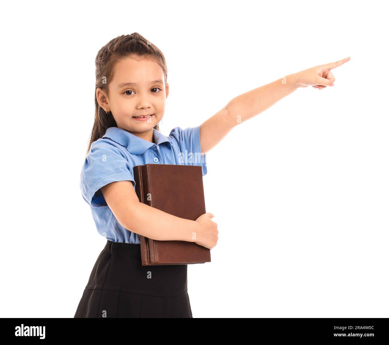 Little schoolgirl with book pointing at something on white background ...