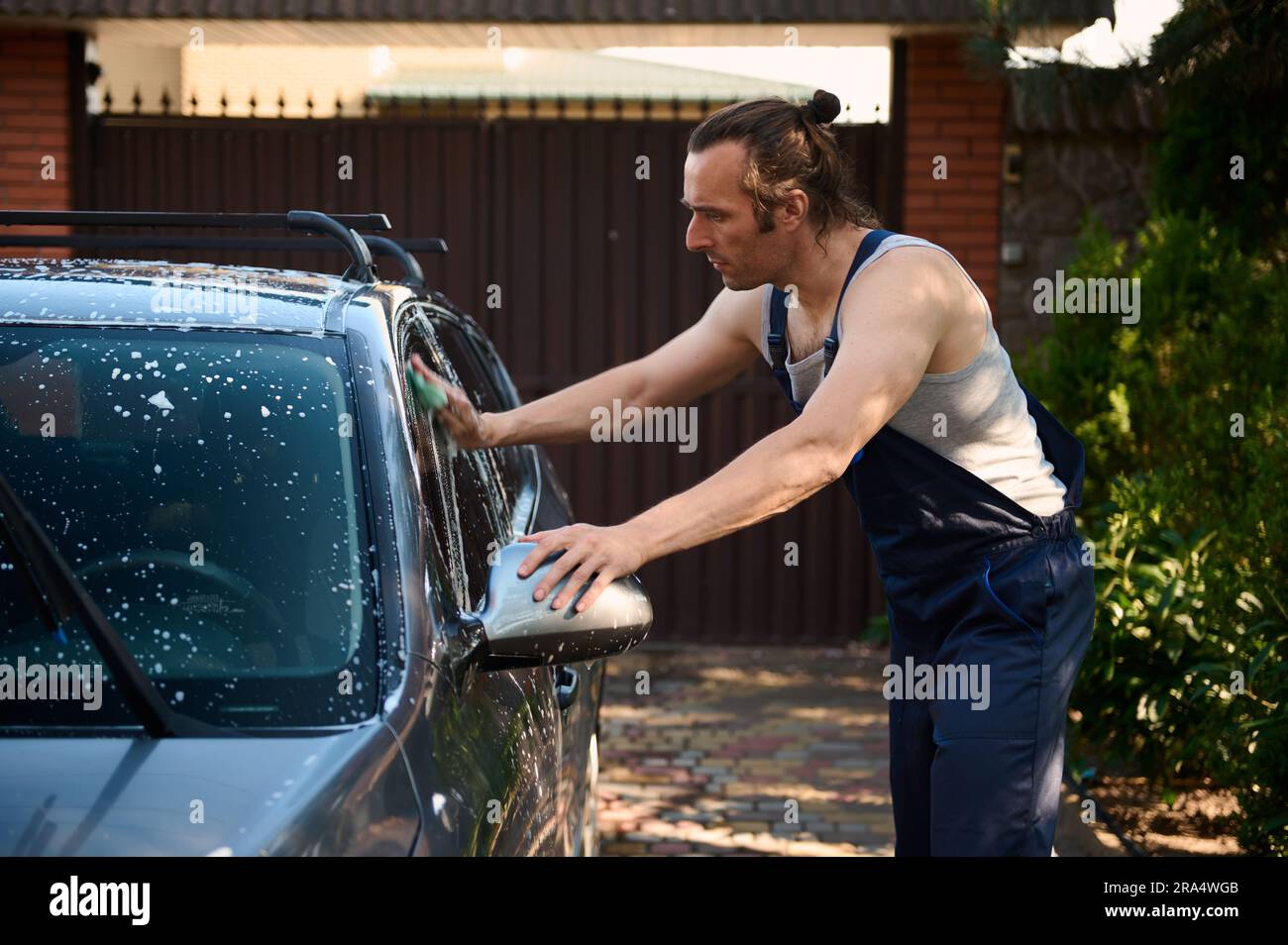 Attractive muscular handsome Caucasian man in blue coverall, manually ...