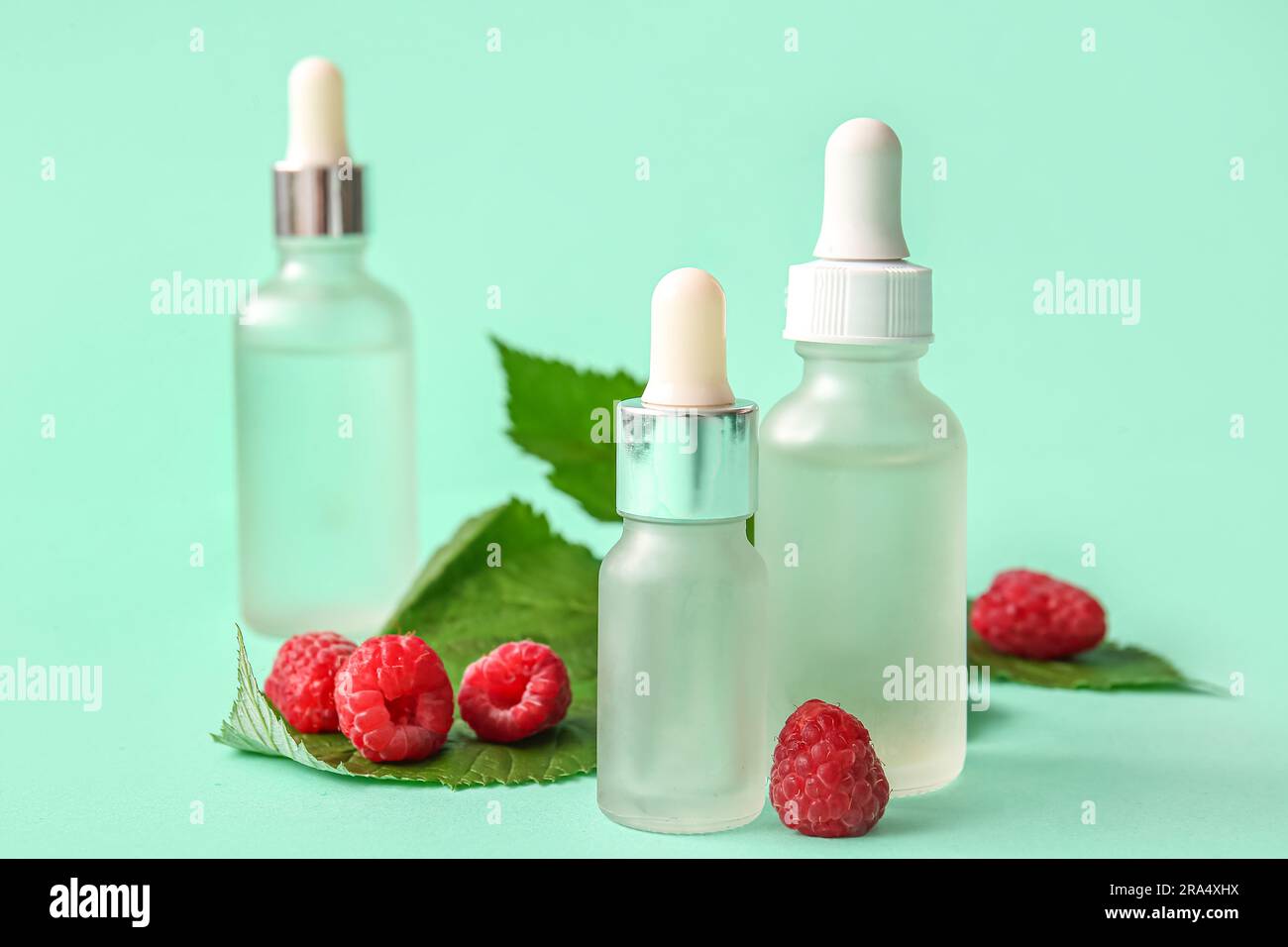 Bottles of cosmetic raspberry oil on blue background Stock Photo - Alamy