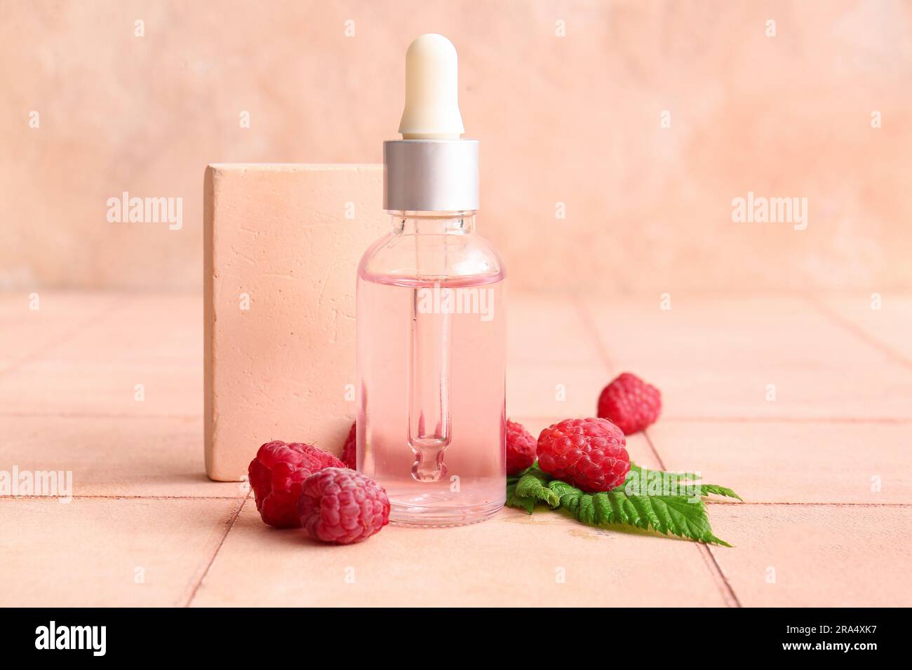 Bottle of cosmetic raspberry oil on pink tile table Stock Photo - Alamy