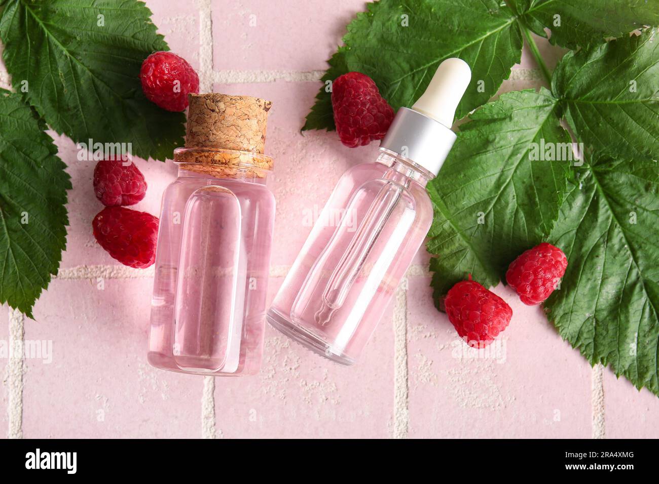 Bottles of cosmetic raspberry oil on pink tile background Stock Photo ...