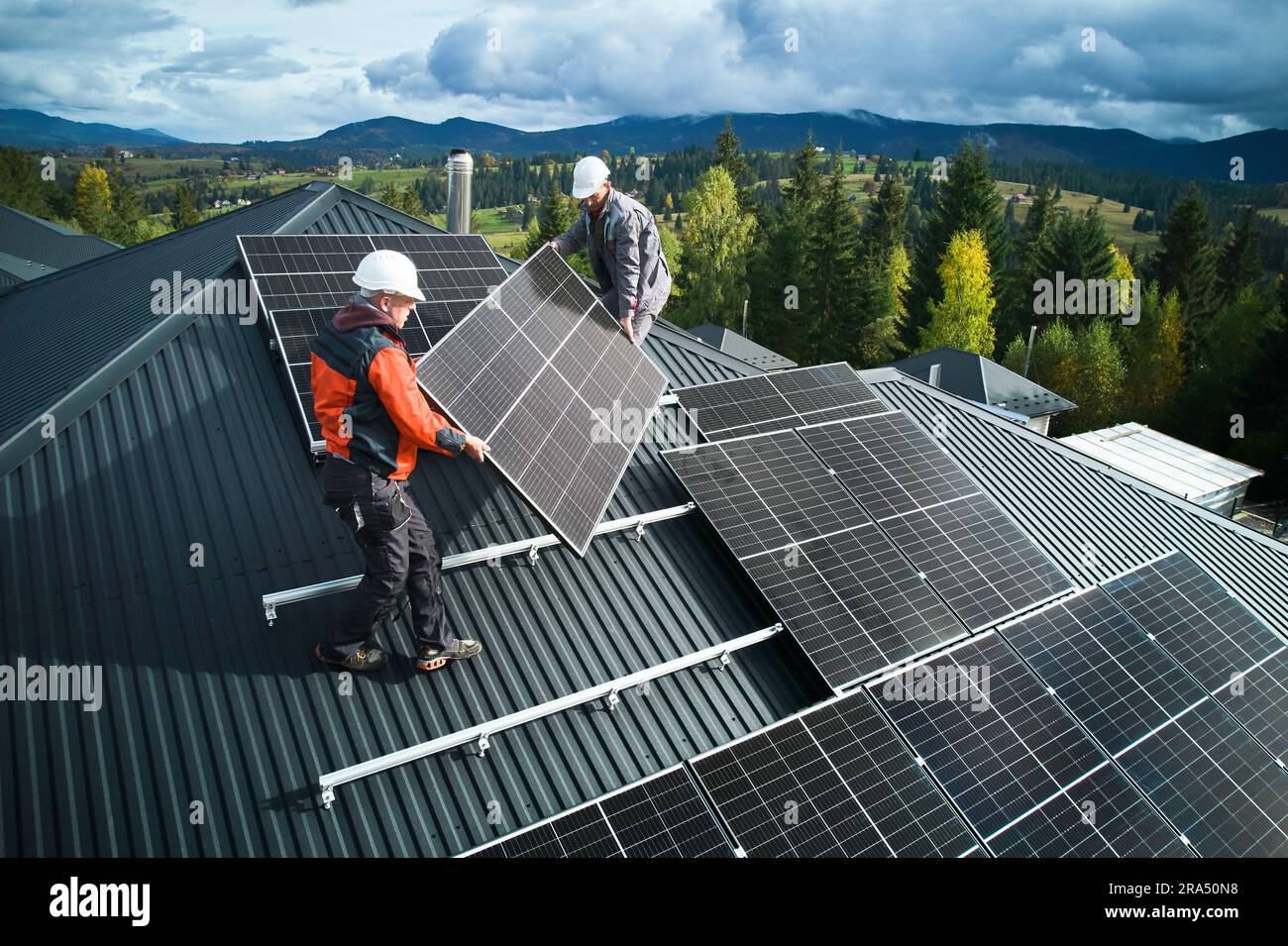 Workers building solar panel system on roof of house. Men technicians ...