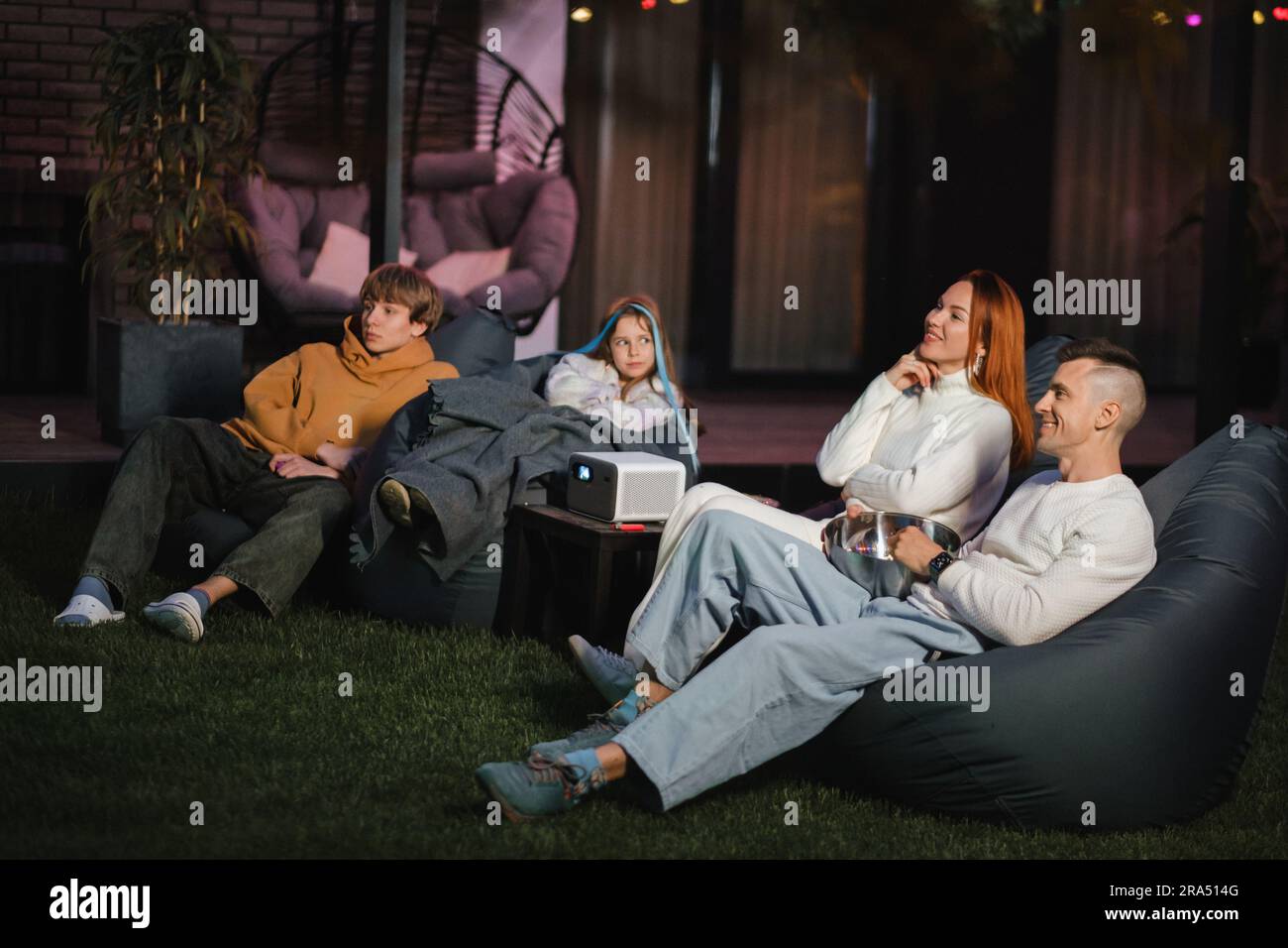 family mother, father and children watch a projector, movies with ...