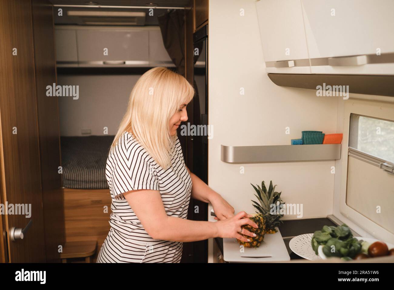 a woman cooking food in the kitchen inside a motorhome, the interior of ...