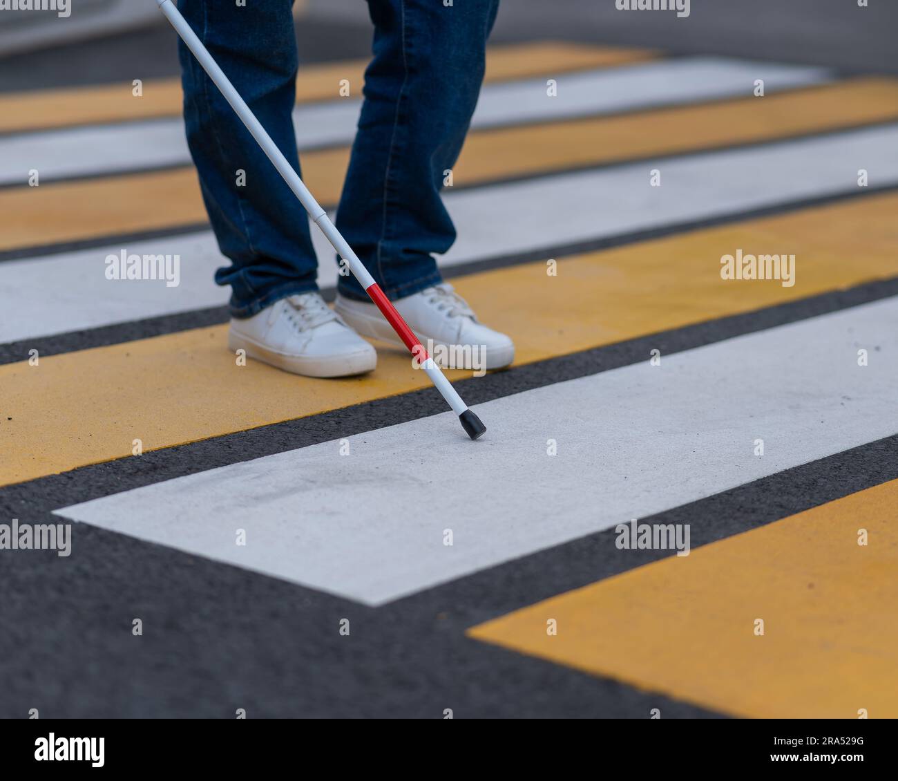 Close-up of the legs of a blind woman crossing the road at a crosswalk ...