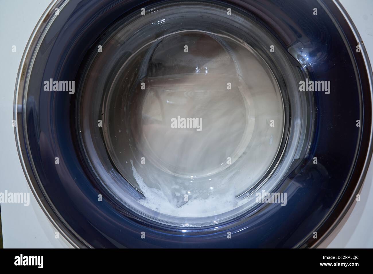 The round door from the washing machine is dark in color, with white ...
