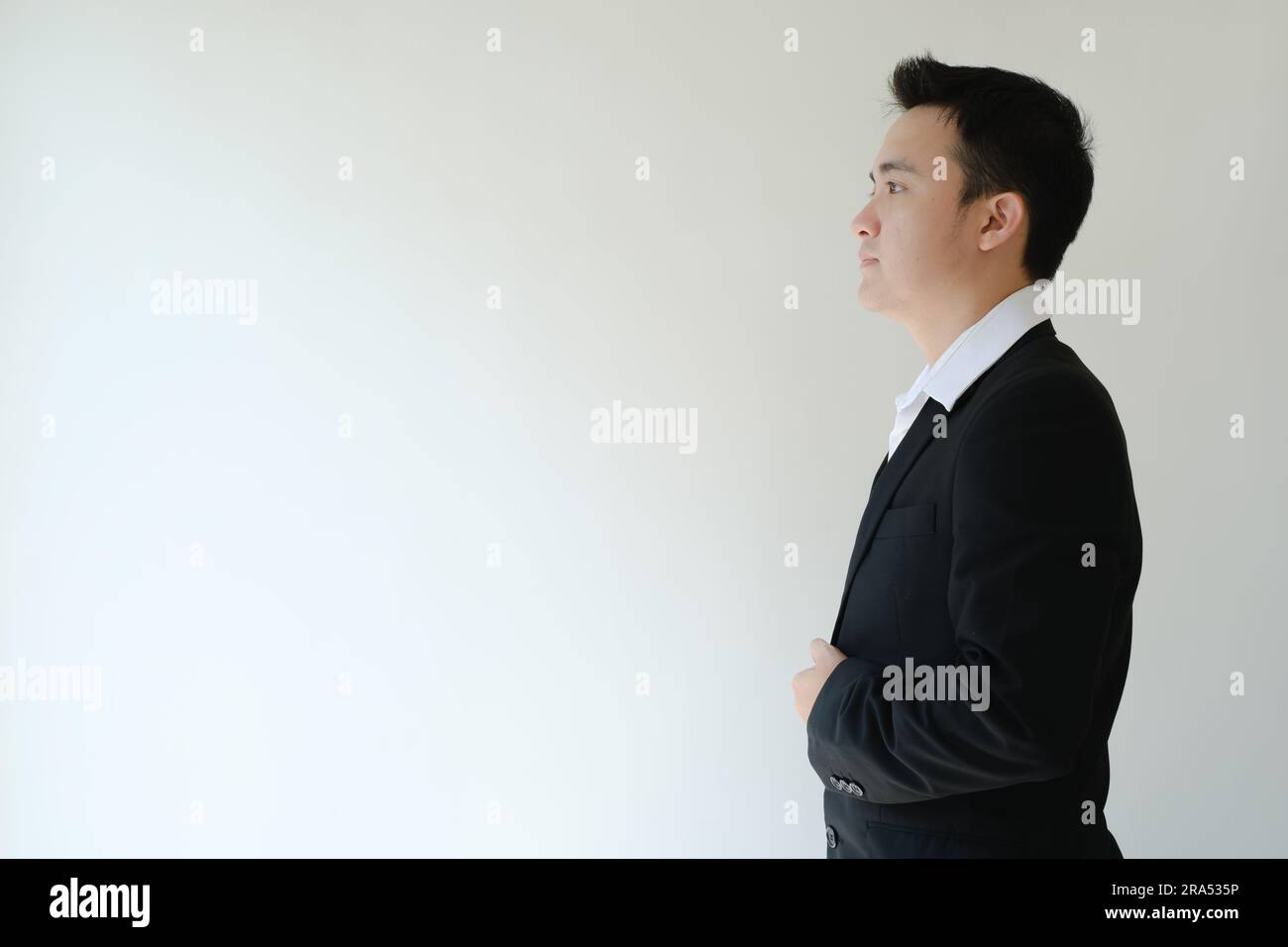 Young Asian business man standing and facing to his right side ...