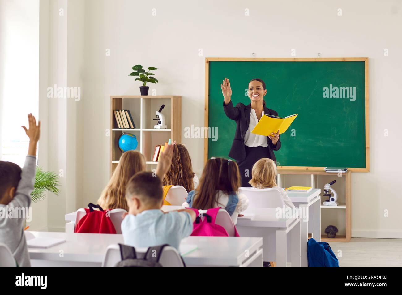 Friendly female teacher conducts lesson for children in modern ...