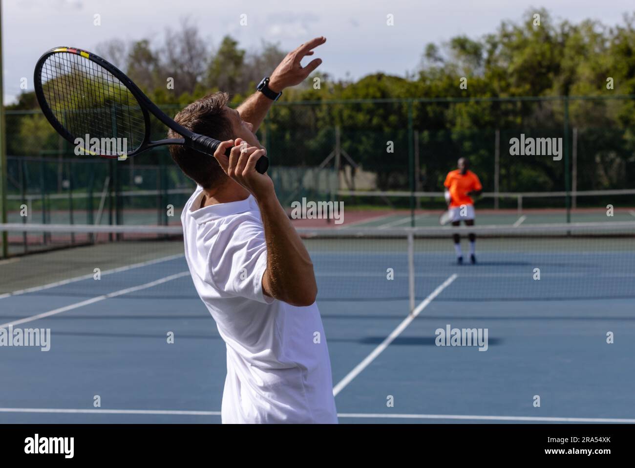Diverse male tennis players playing tennis on outdoor tennis court ...