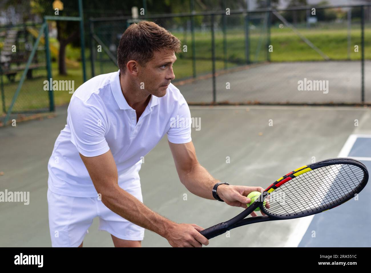 Focused caucasian male tennis player playing tennis serving ball on ...