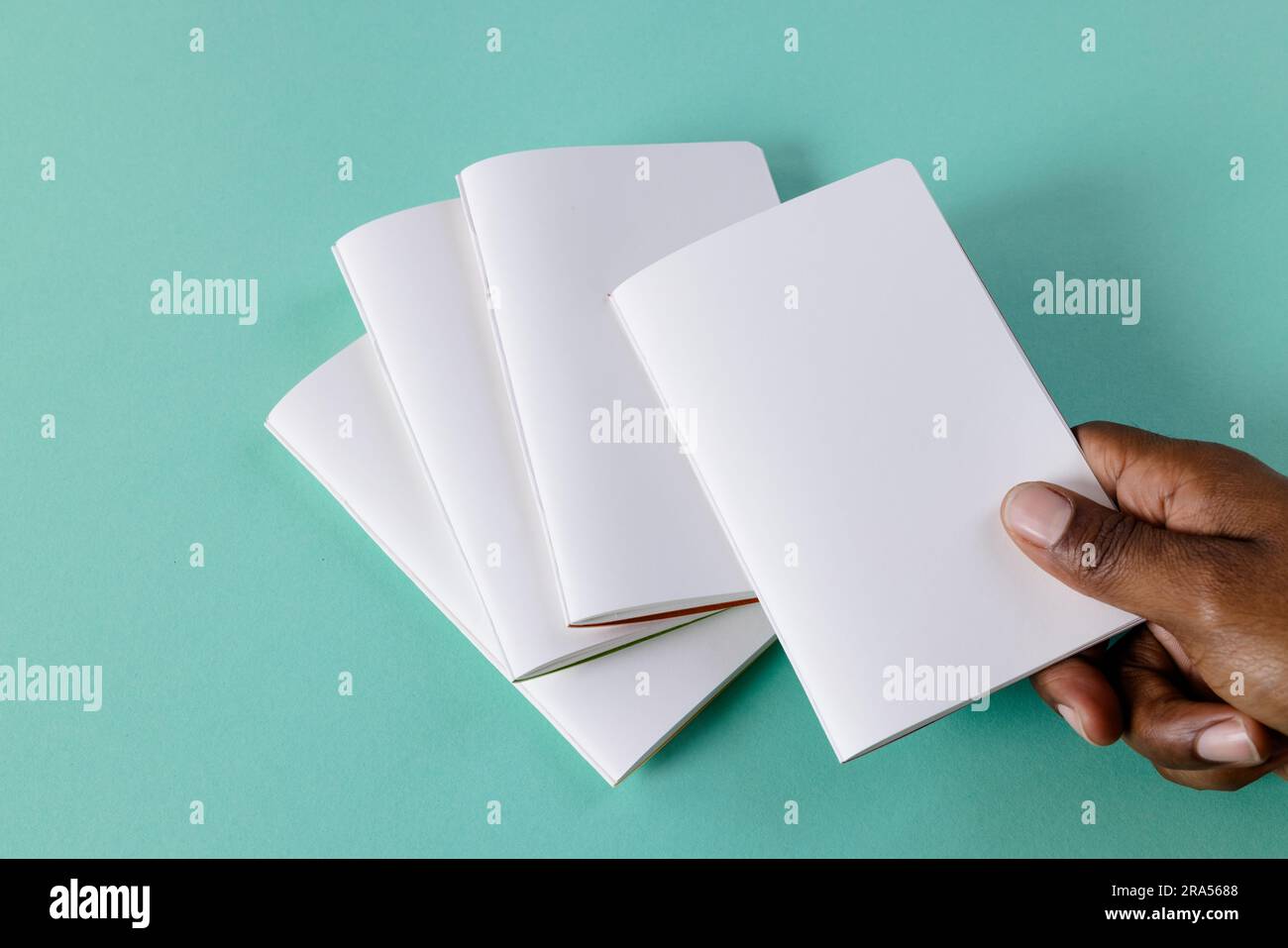 Hand of biracial man holding notebook over notebooks with copy space on ...