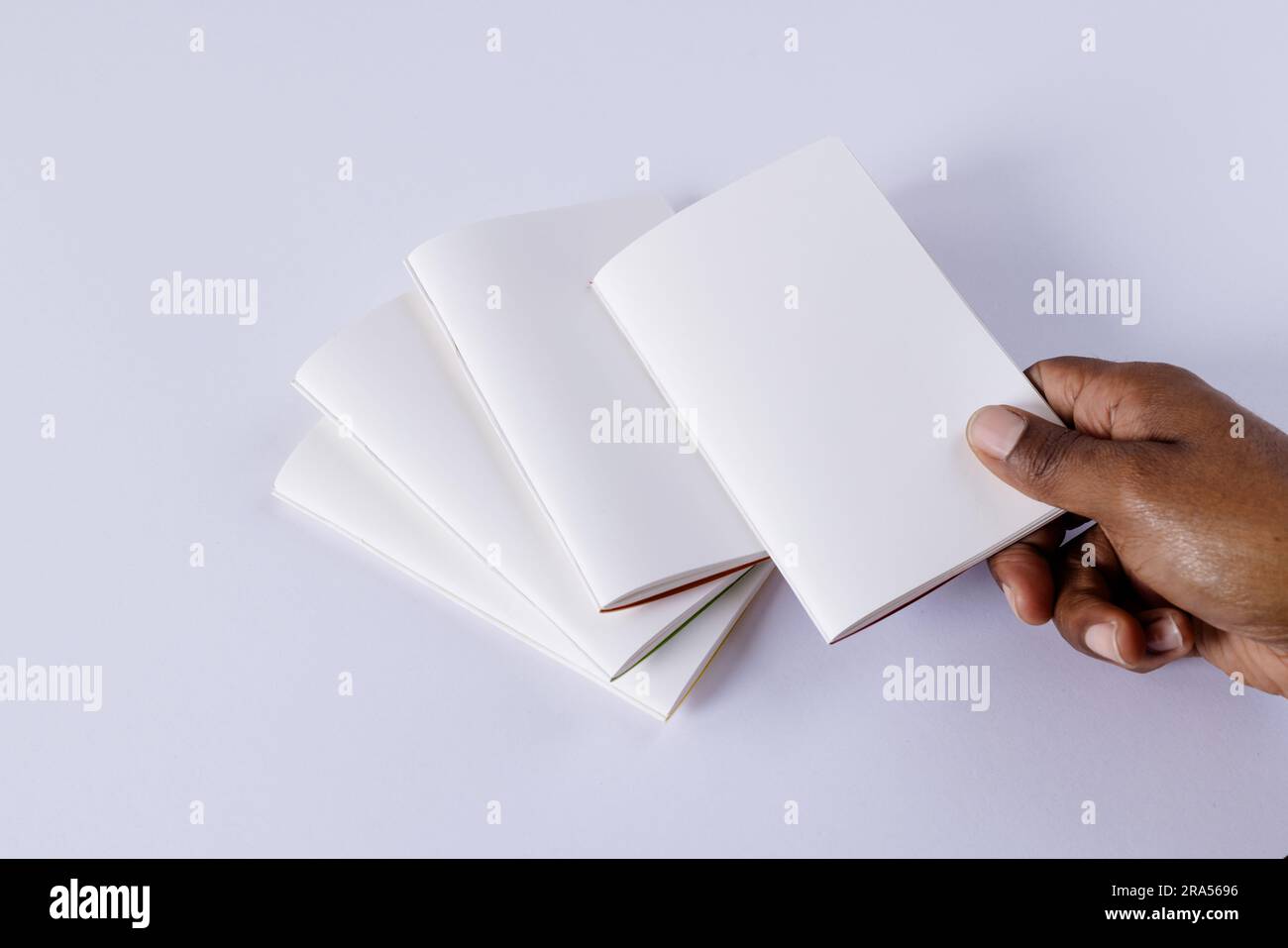 Hand of biracial man holding notebook over notebooks with copy space on ...