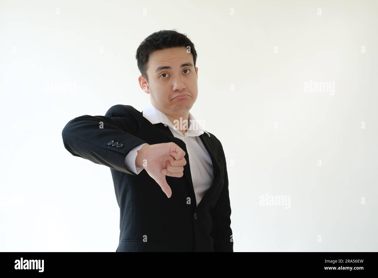 Young Asian business man with dislike face expression giving thumb down ...