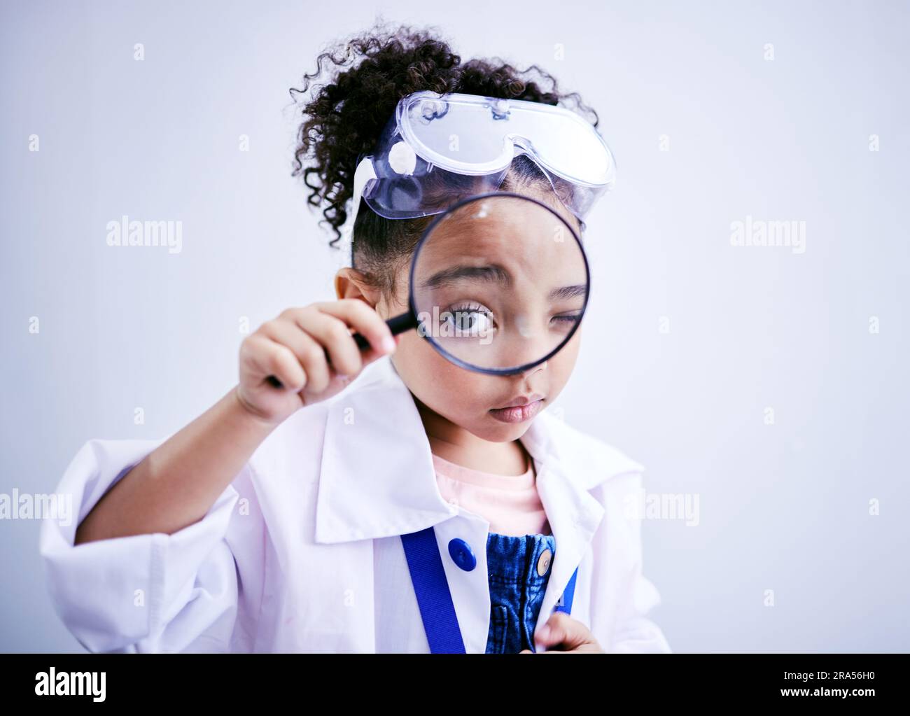Child, magnifying glass and portrait of a scientist girl in studio with ...