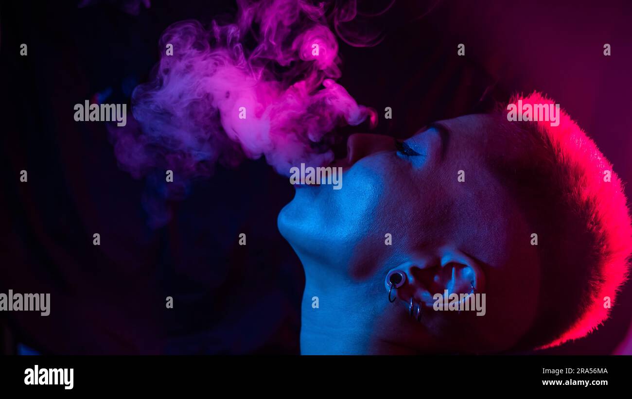Close up portrait of asian woman with short hair smoking in neon light ...