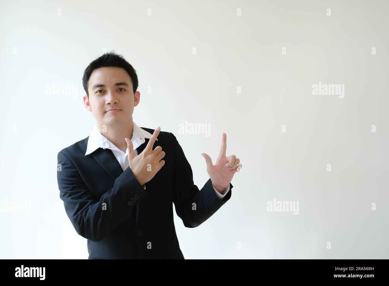 Young Asian business man pointing to his upper left side and looking at ...