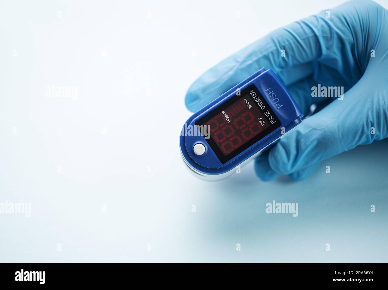 Pulse oximeter in doctor hand with glove on blue background. A hand in ...