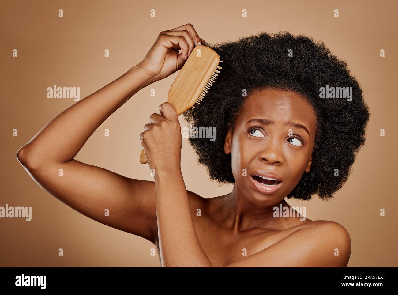 Black woman, problem and brushing hair in studio, brown background and ...