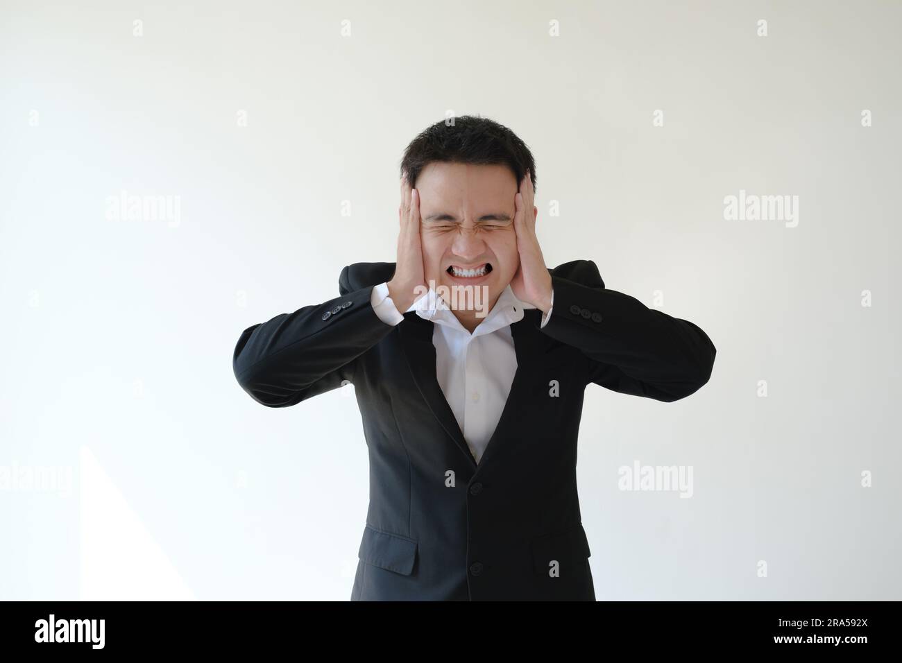 A young Asian businessman wearing a white shirt with a black suit is ...