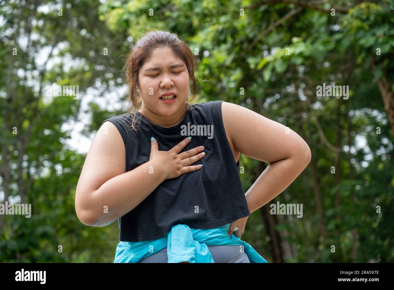 Overweight young woman with chest pain putting her right hand over her ...
