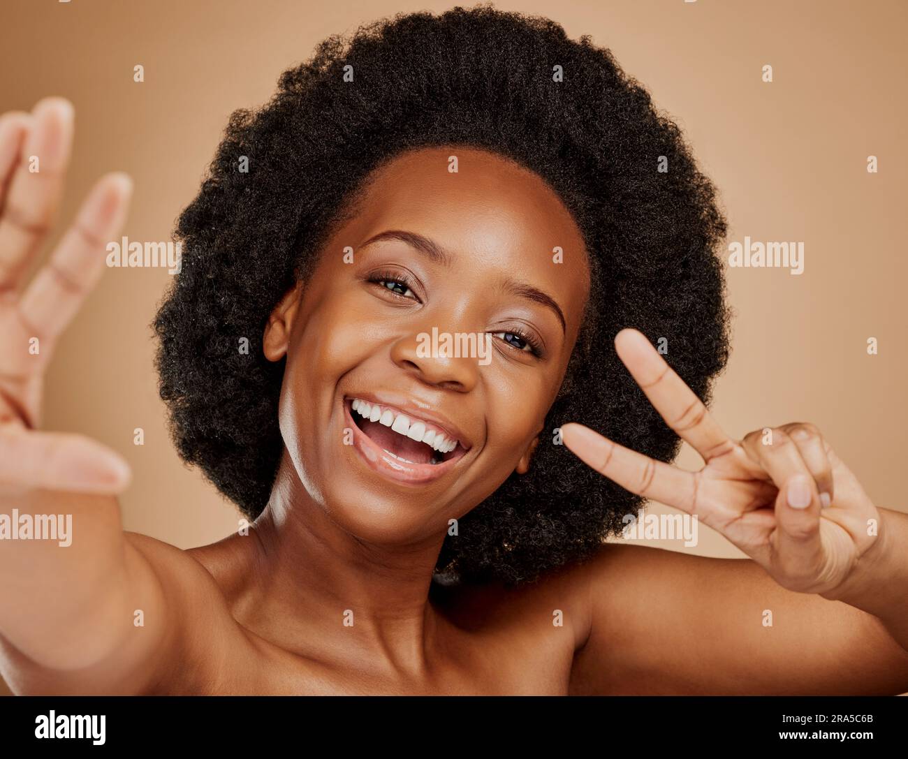 Face, black woman and selfie, peace sign and beauty in studio isolated on a brown background ...