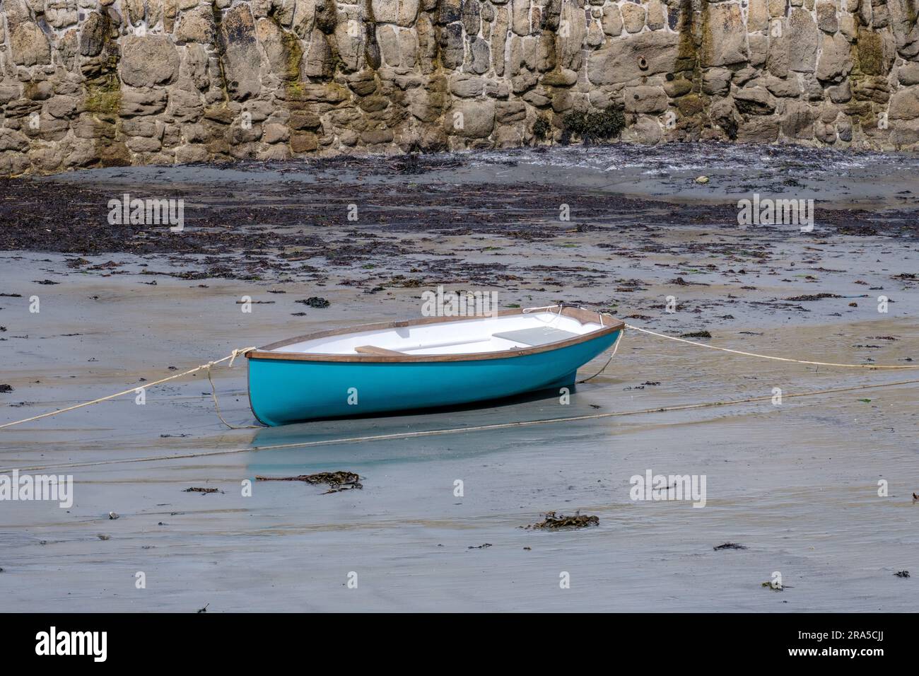 Close-up of a row boat sitting beached at low tide with an ancient ...