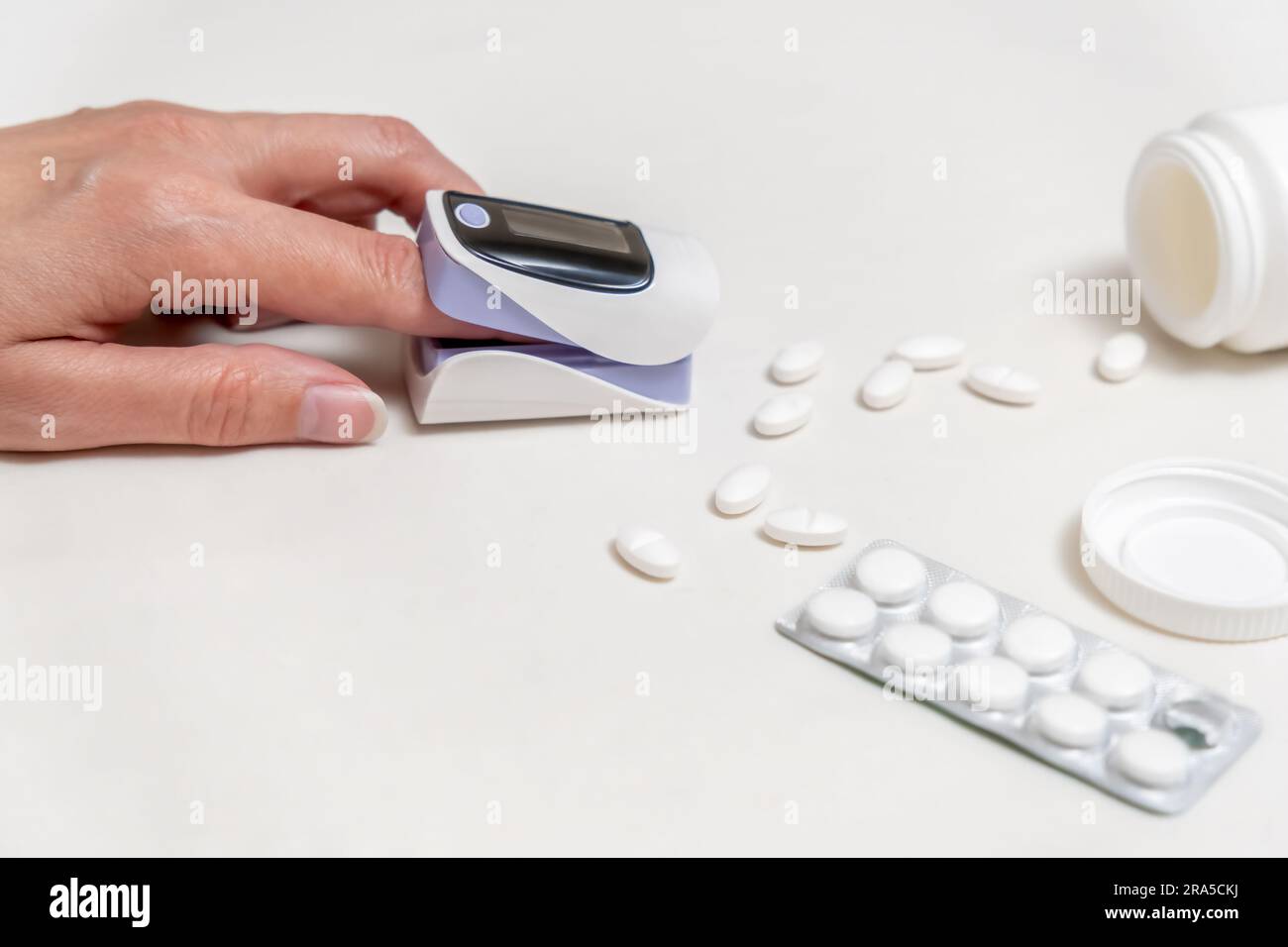 pulse oximeter on finger and pills on table, healthcare monitoring ...