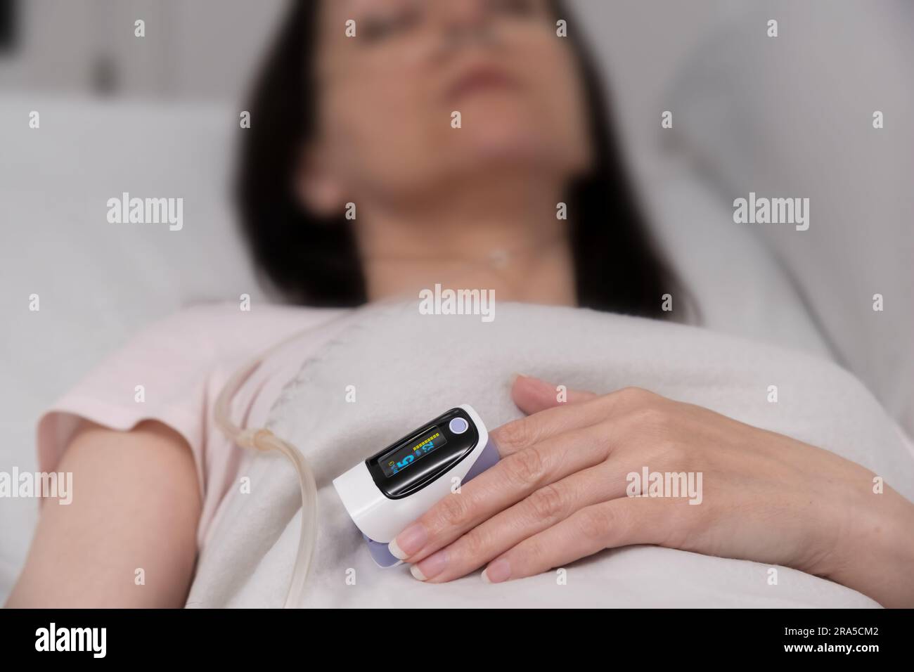 pulse oximeter on the finger close-up. patient in the hospital on a bed ...