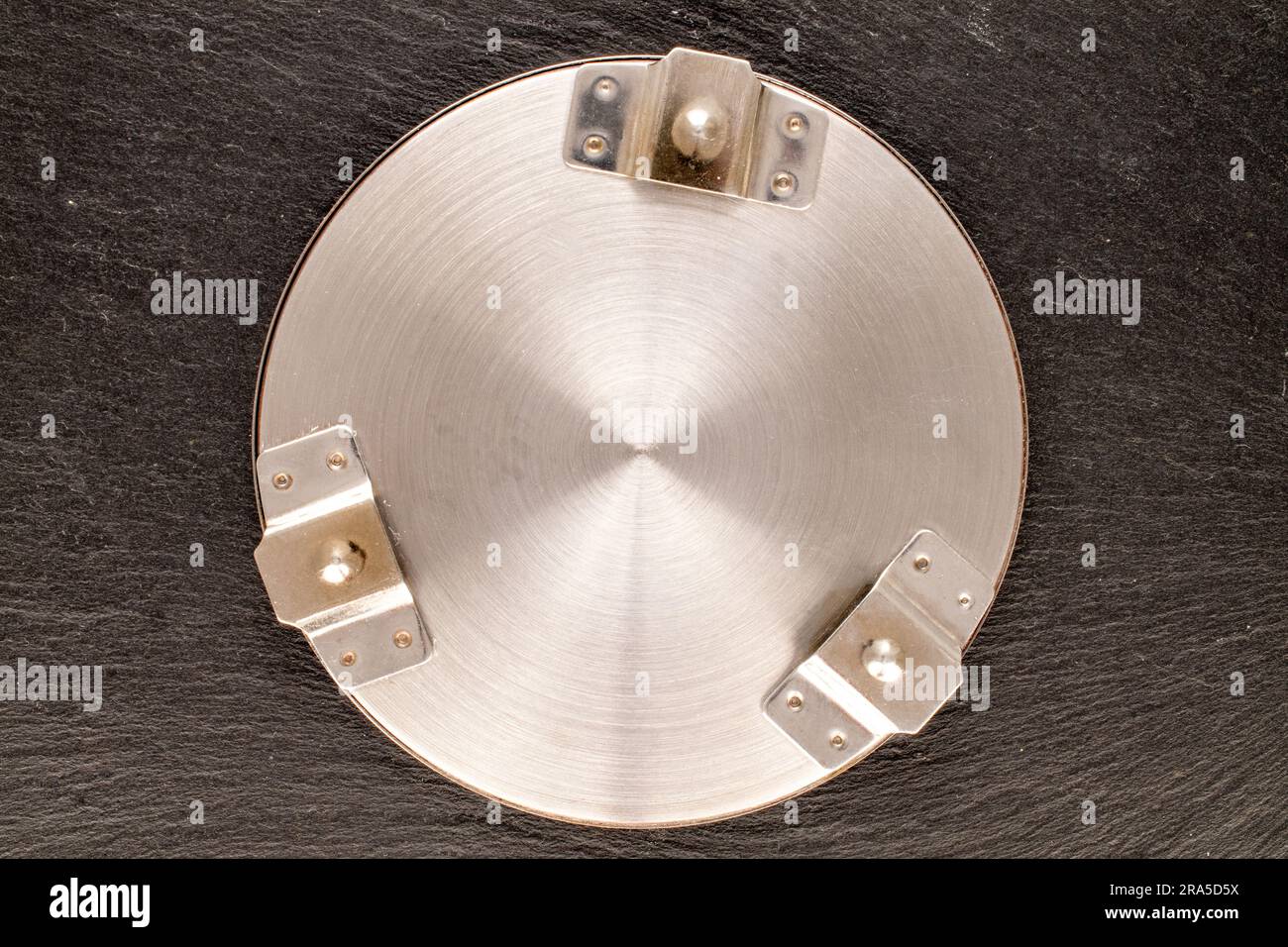 One metal adapter for induction surface on slate stone, macro, top view ...