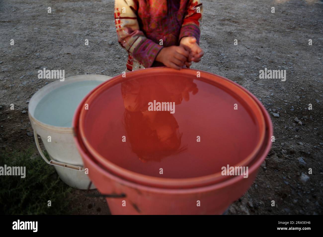 FILED - 21 June 2023, Iran, Zabol: A child's face reflected in a bucket ...