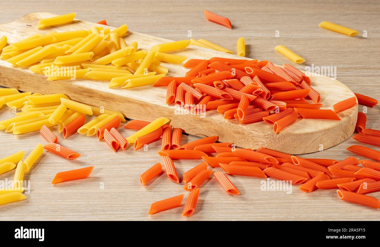 Italian pasta in bright red and yellow color is scattered on the ...