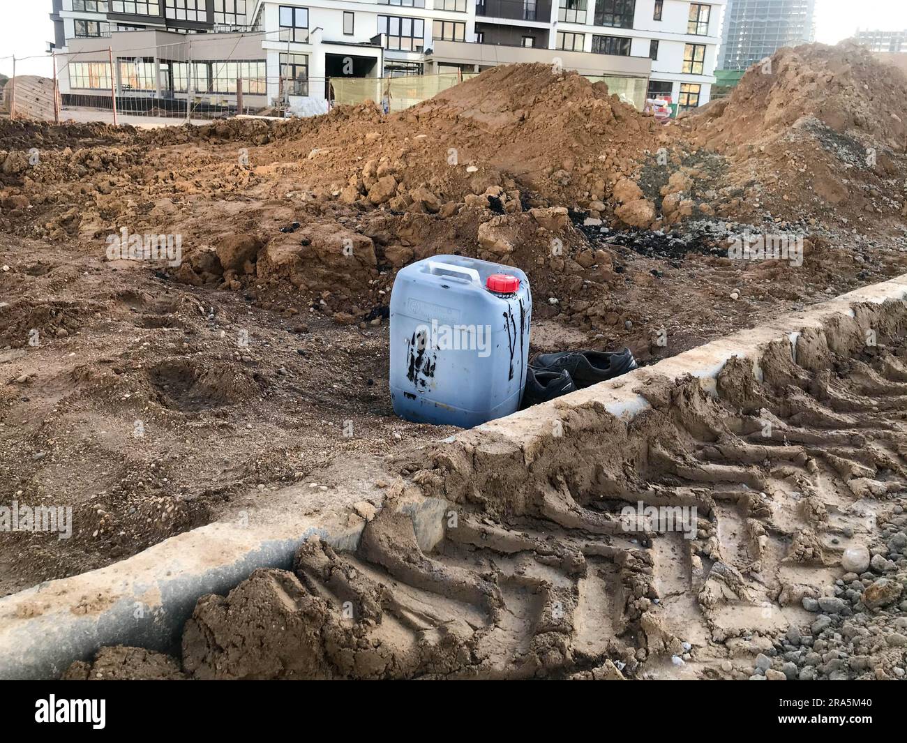 a white construction canister with a red lid is on the ground. the ...