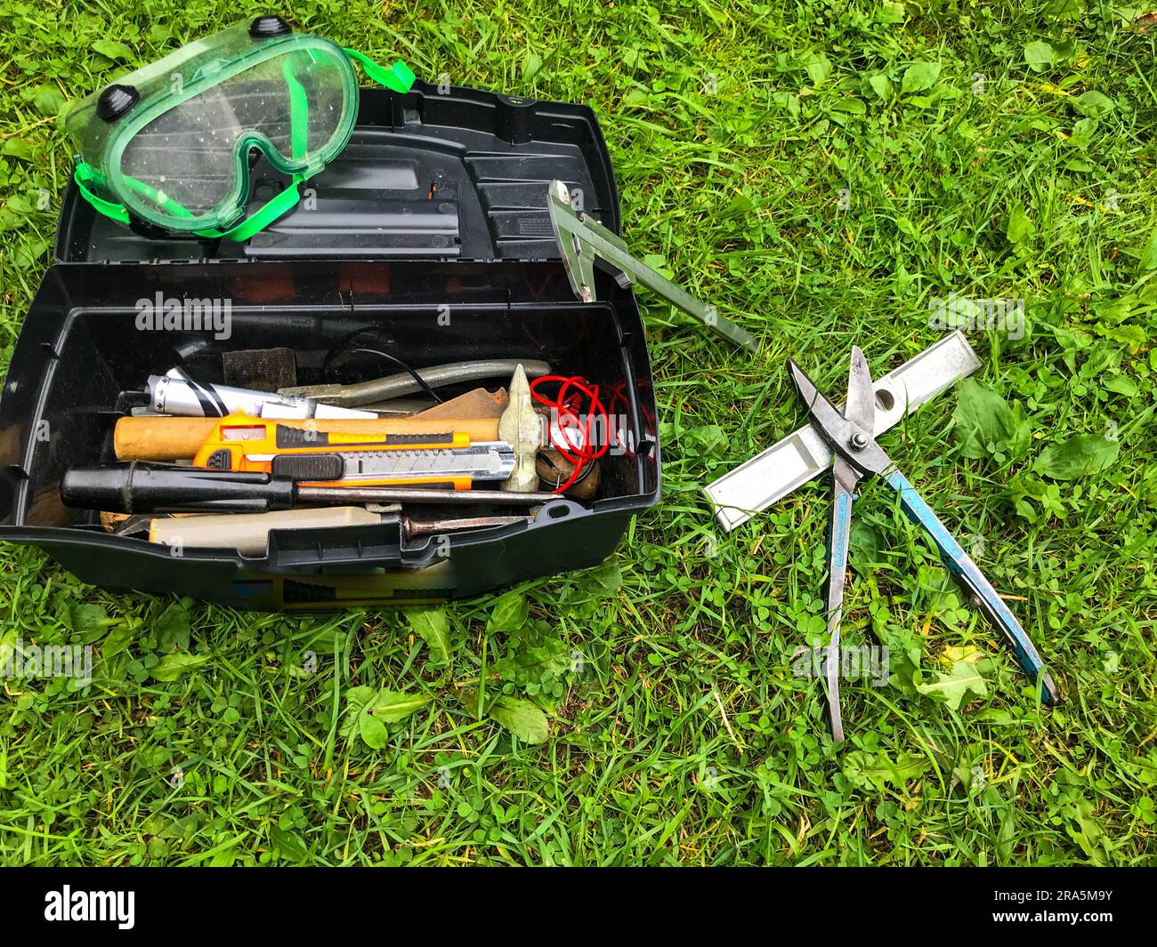a black toolbox stands on the ground, on a green lawn. inside the box ...