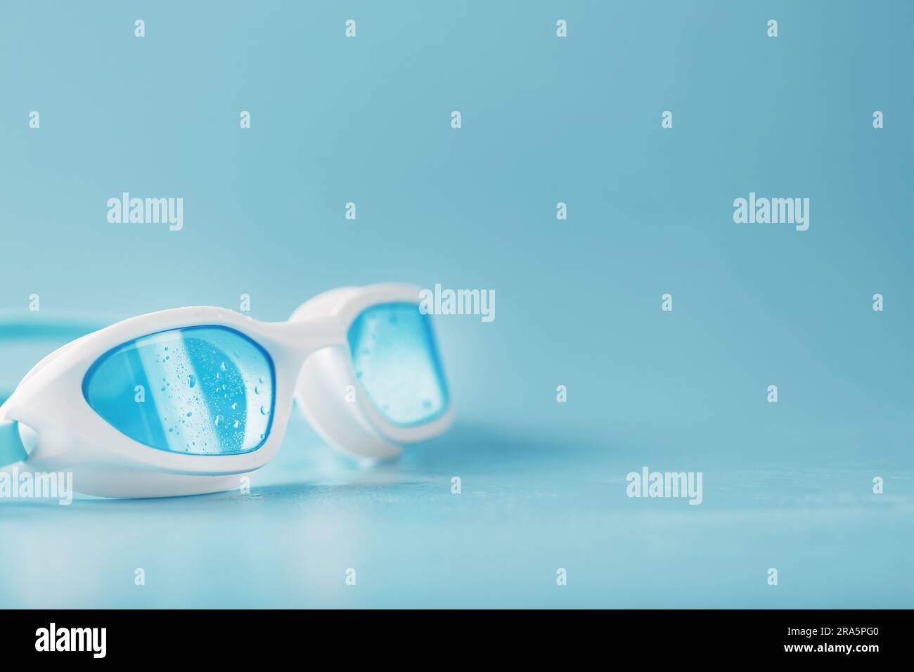 White swimming goggles on a blue background in a minimalist style with ...