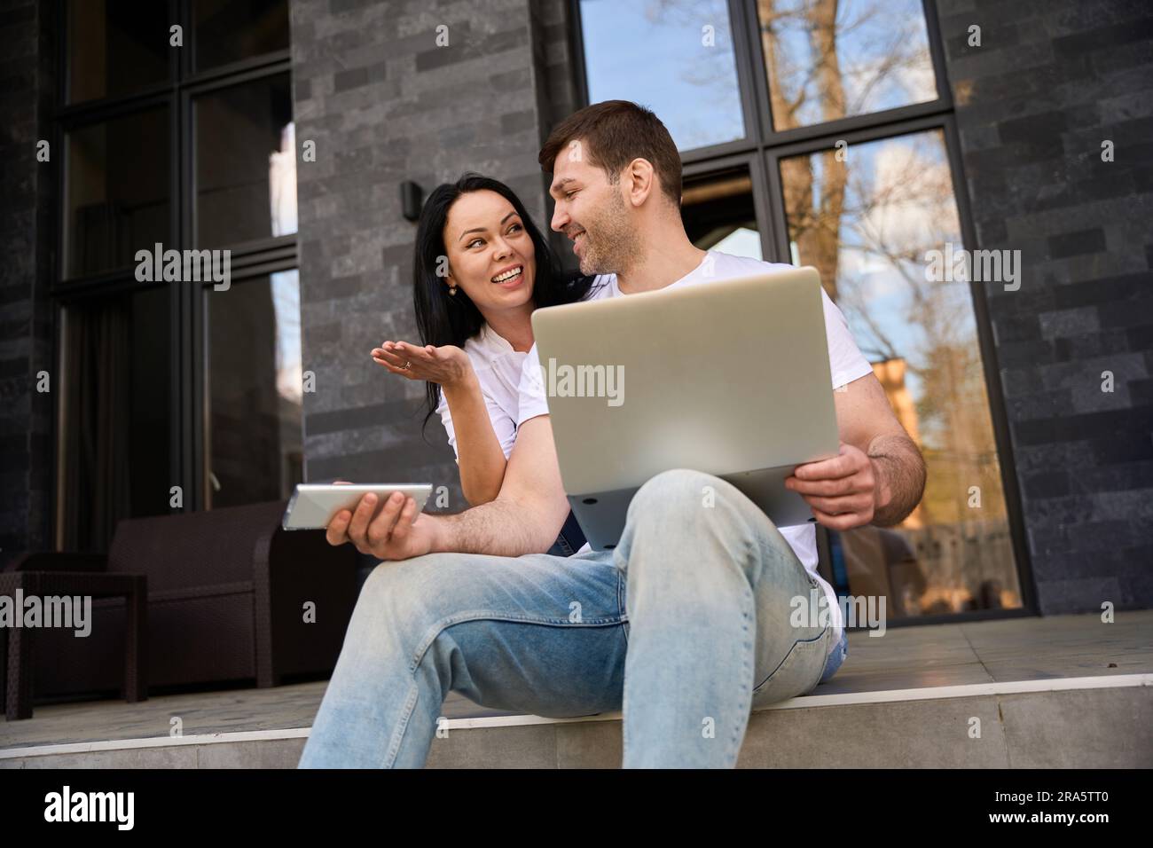 Caucasian couple sitting on the steps near the house Stock Photo - Alamy