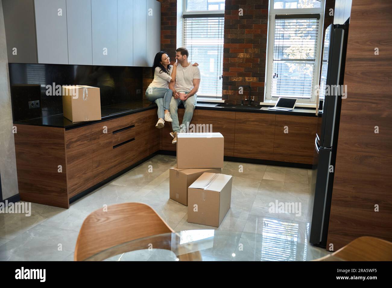 Two people are sitting on a table in the kitchen Stock Photo - Alamy