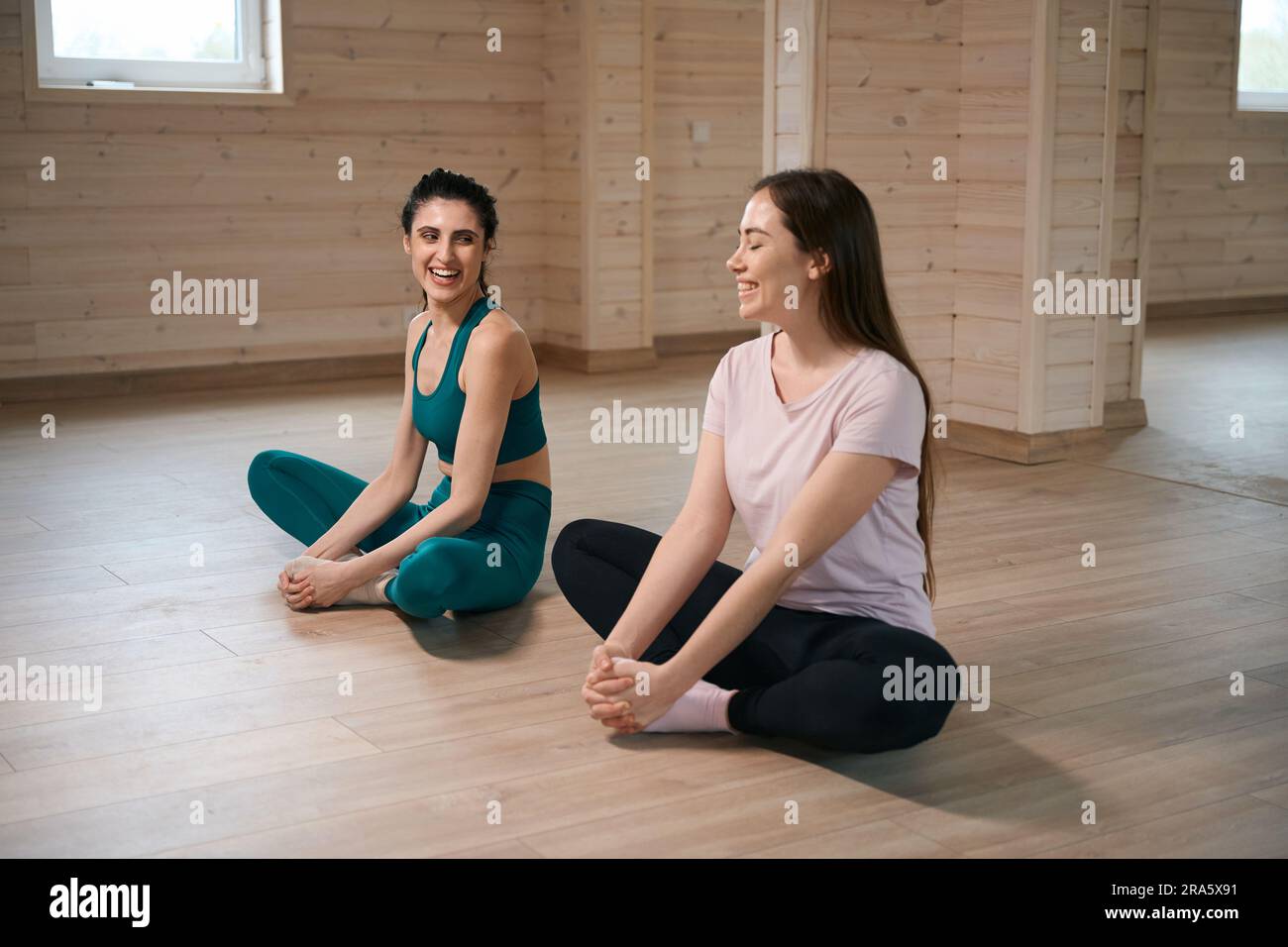 Smiling woman and trainer sitting in butterfly pose Stock Photo - Alamy