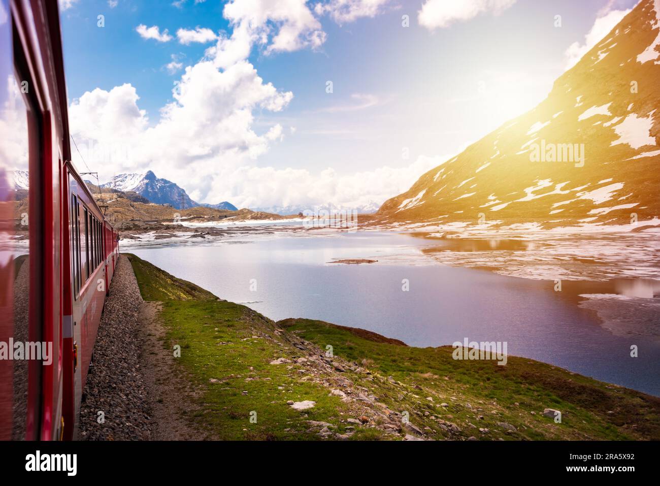 Train going along lake in Switzerland with some ice, swiss alps ...