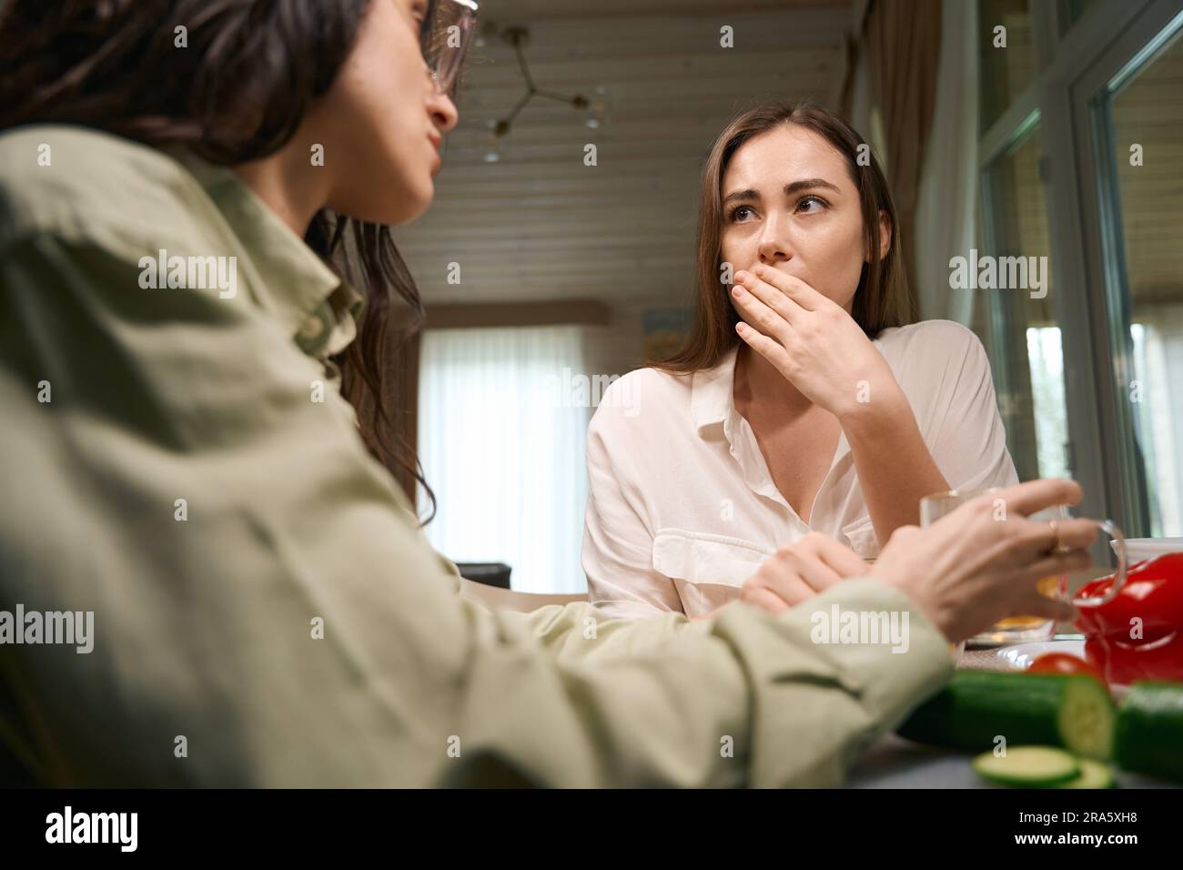 Female friends communicate at desk and holding cup Stock Photo - Alamy