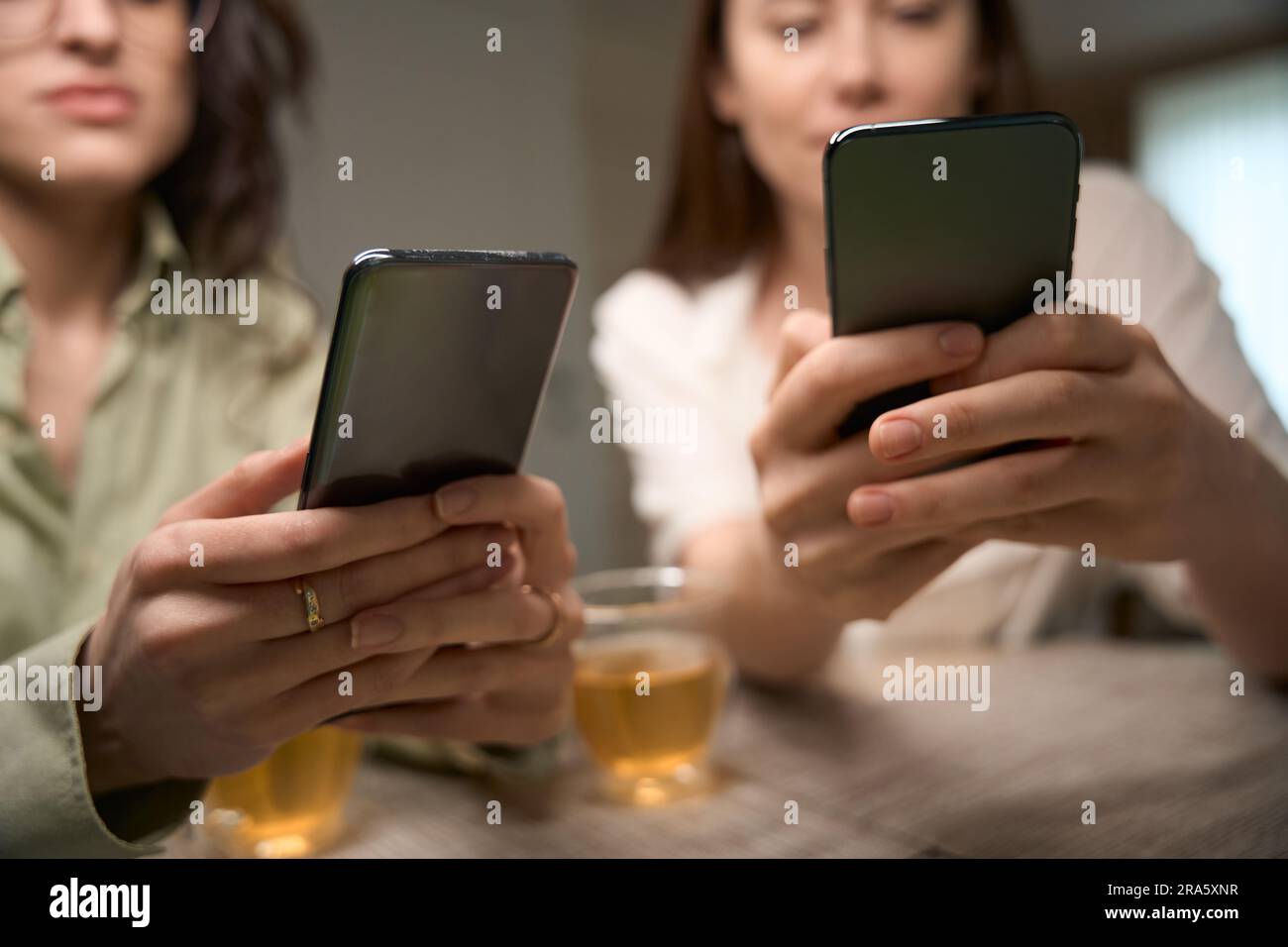Close up photo of female friends using phones Stock Photo - Alamy